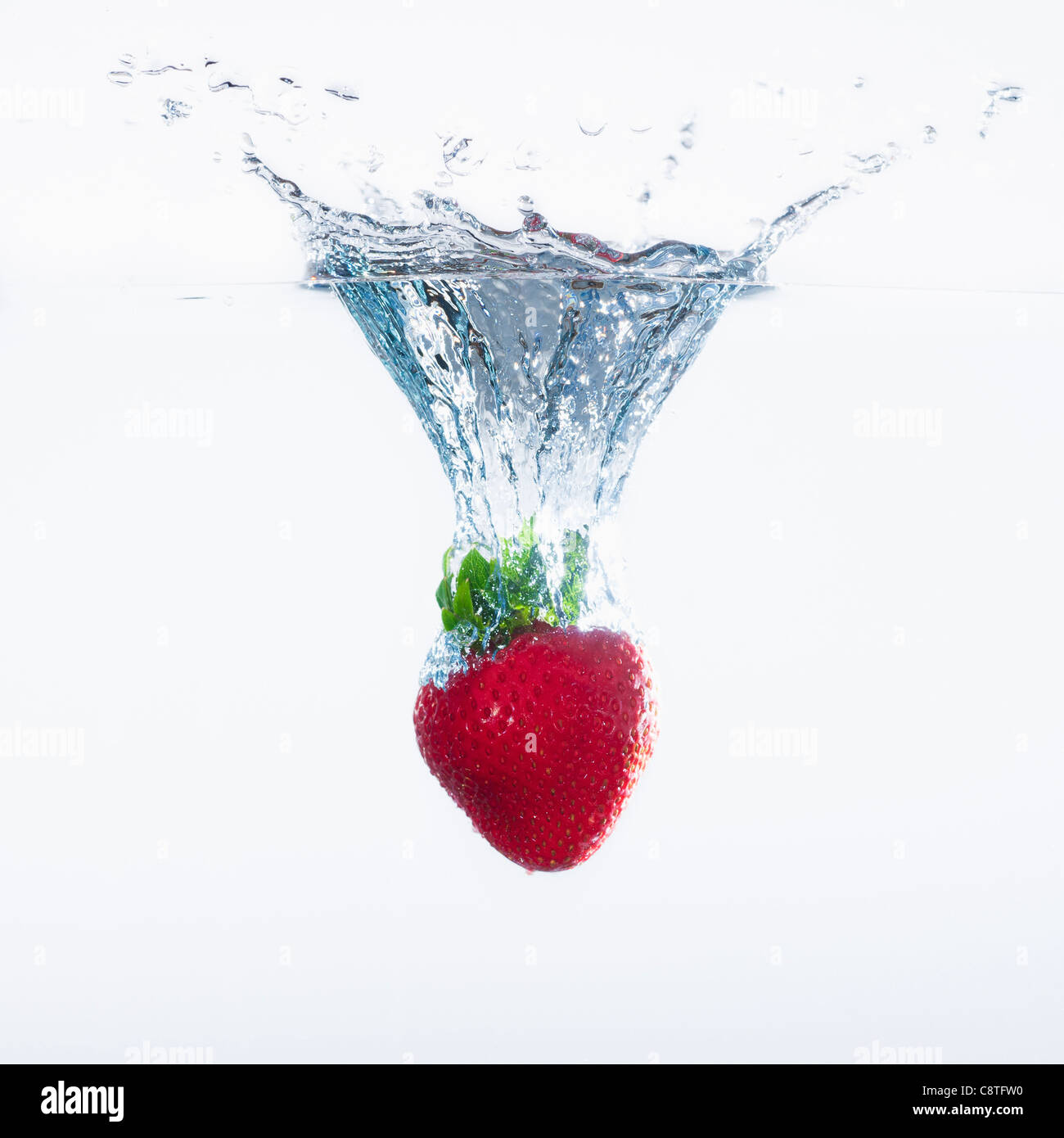 Strawberry splashing into water, studio shot Stock Photo - Alamy