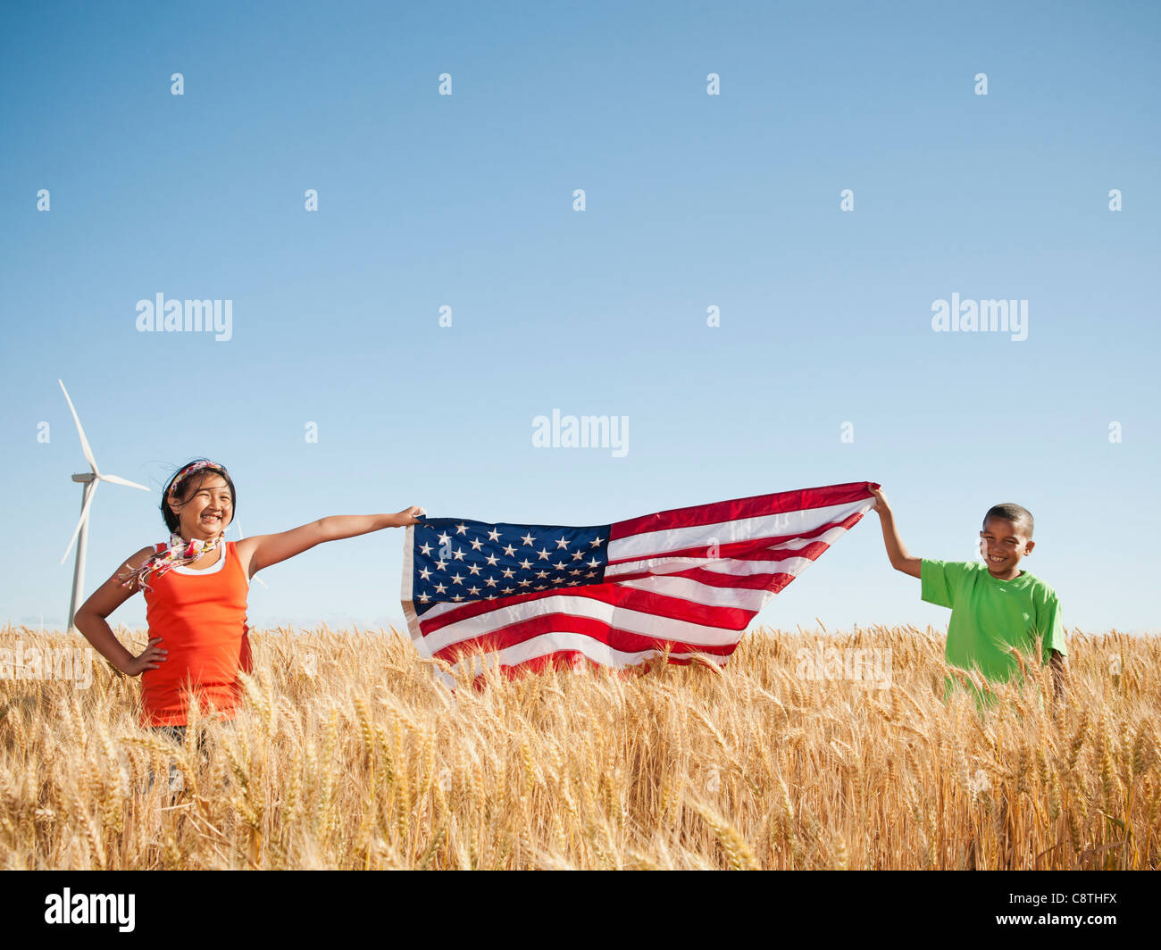 USA, Oregon, Wasco, Girl holding american flag in wheat field , wind ...
