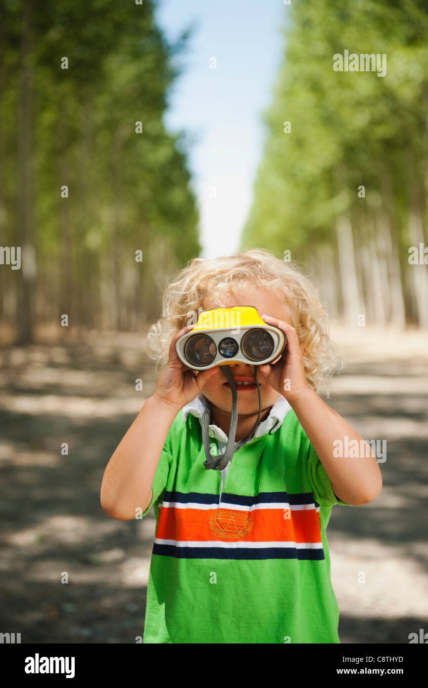 USA, Oregon, Boardman, Boy looking through binoculars in tree farm ...