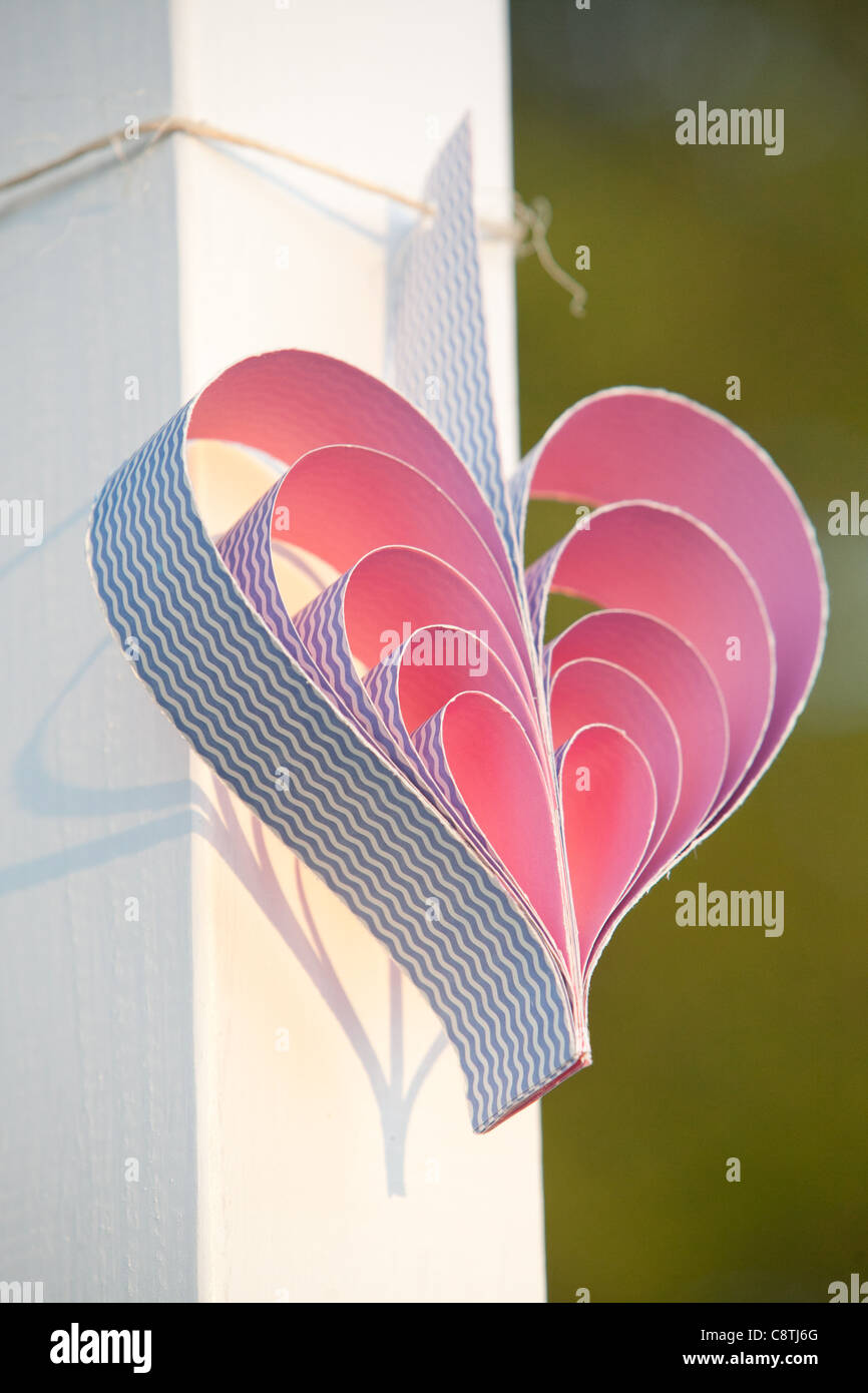A striped paper heart decoration with pink hanging in the golden ...