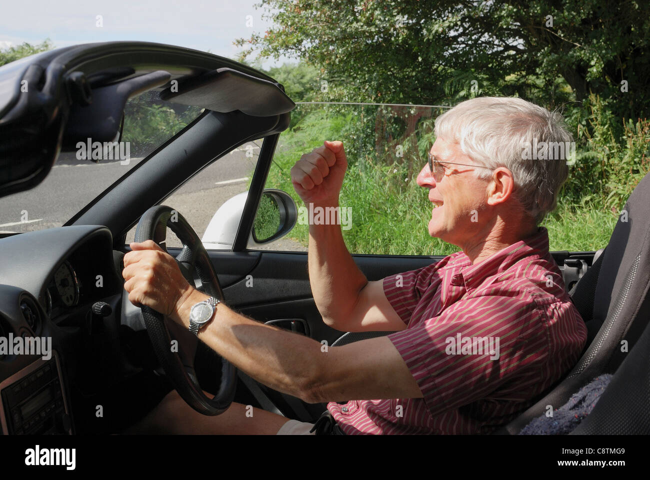 Male driver in sports car showing anger and waving fist Stock Photo - Alamy