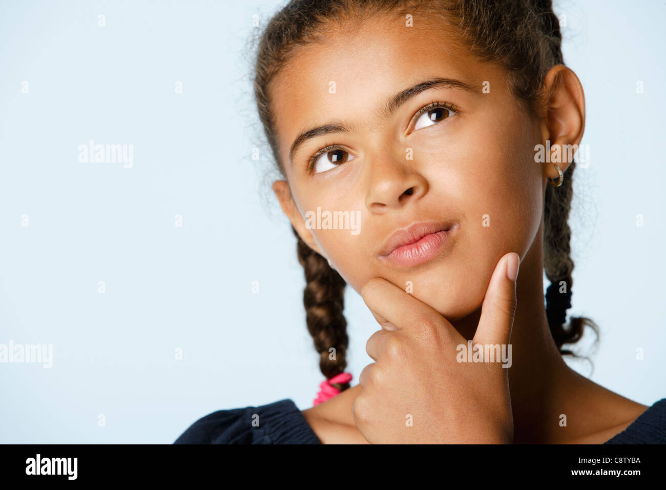Studio portrait of girl with hand on chin, looking up Stock Photo - Alamy