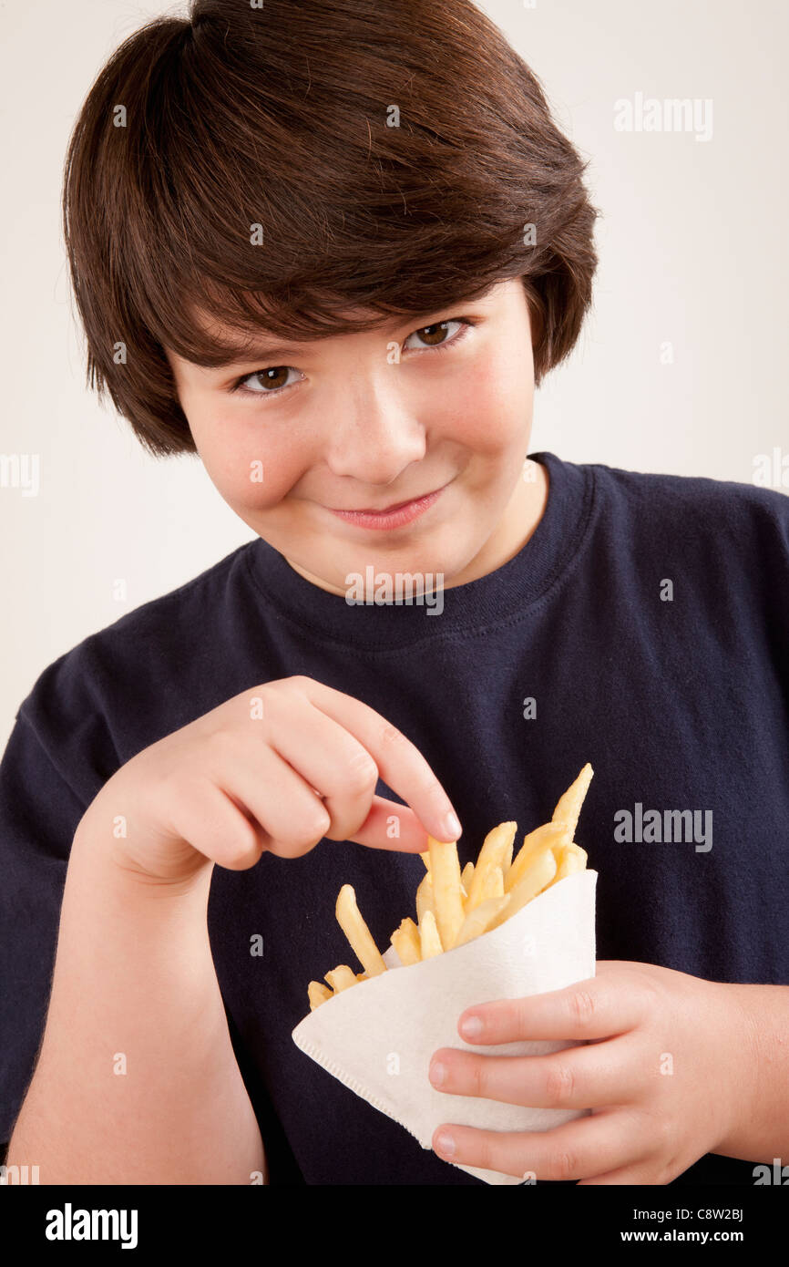 Studio portrait of boy holding french fries Stock Photo - Alamy