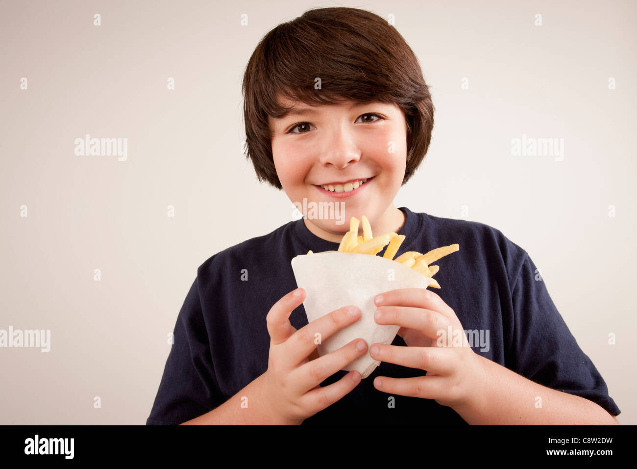 Studio portrait of boy holding french fries Stock Photo - Alamy