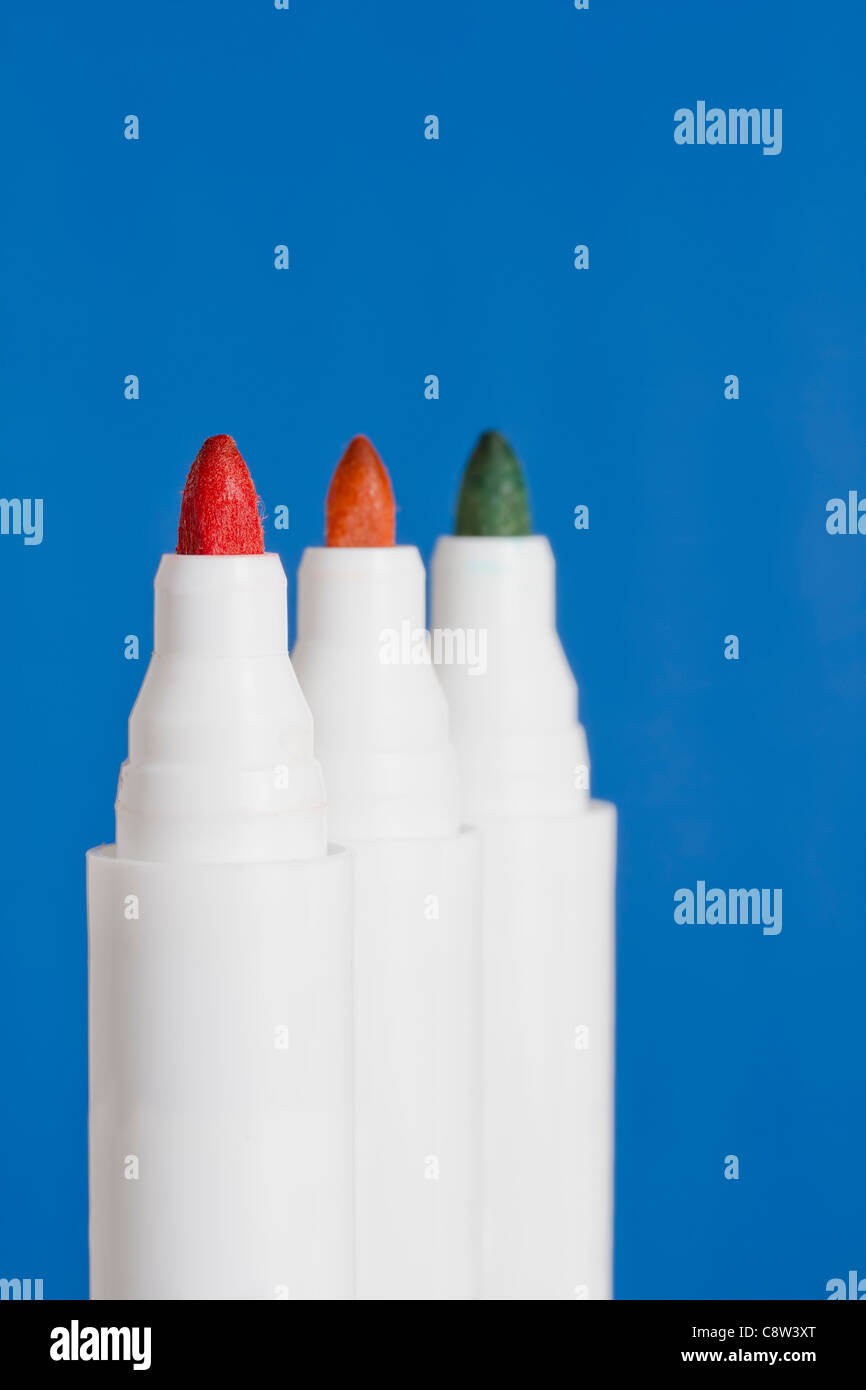 Three coloured marker pens on blue background Stock Photo - Alamy