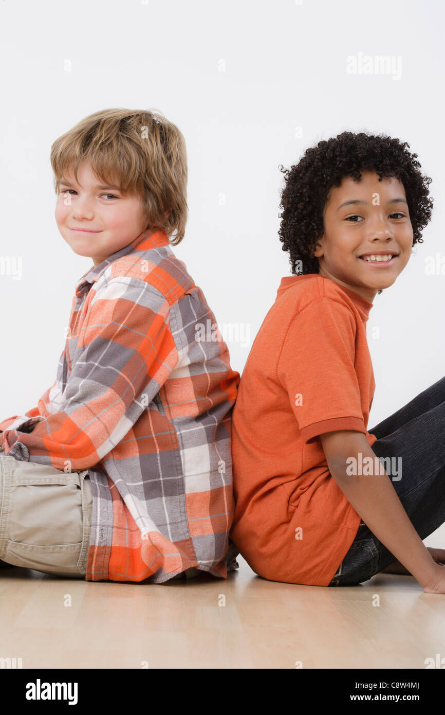 Studio portrait of two boys sitting back to back Stock Photo - Alamy