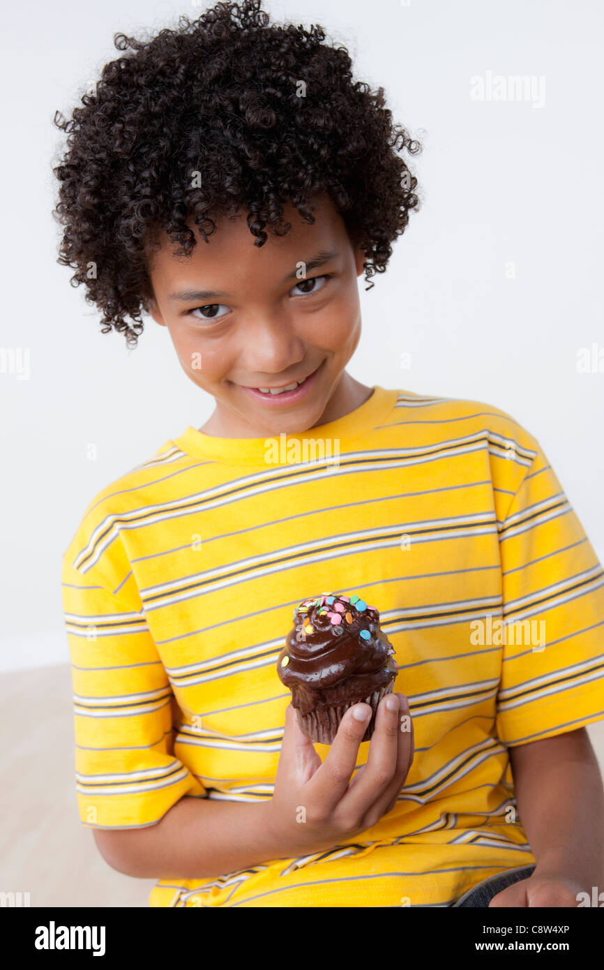 Studio portrait of boy holding muffin Stock Photo - Alamy