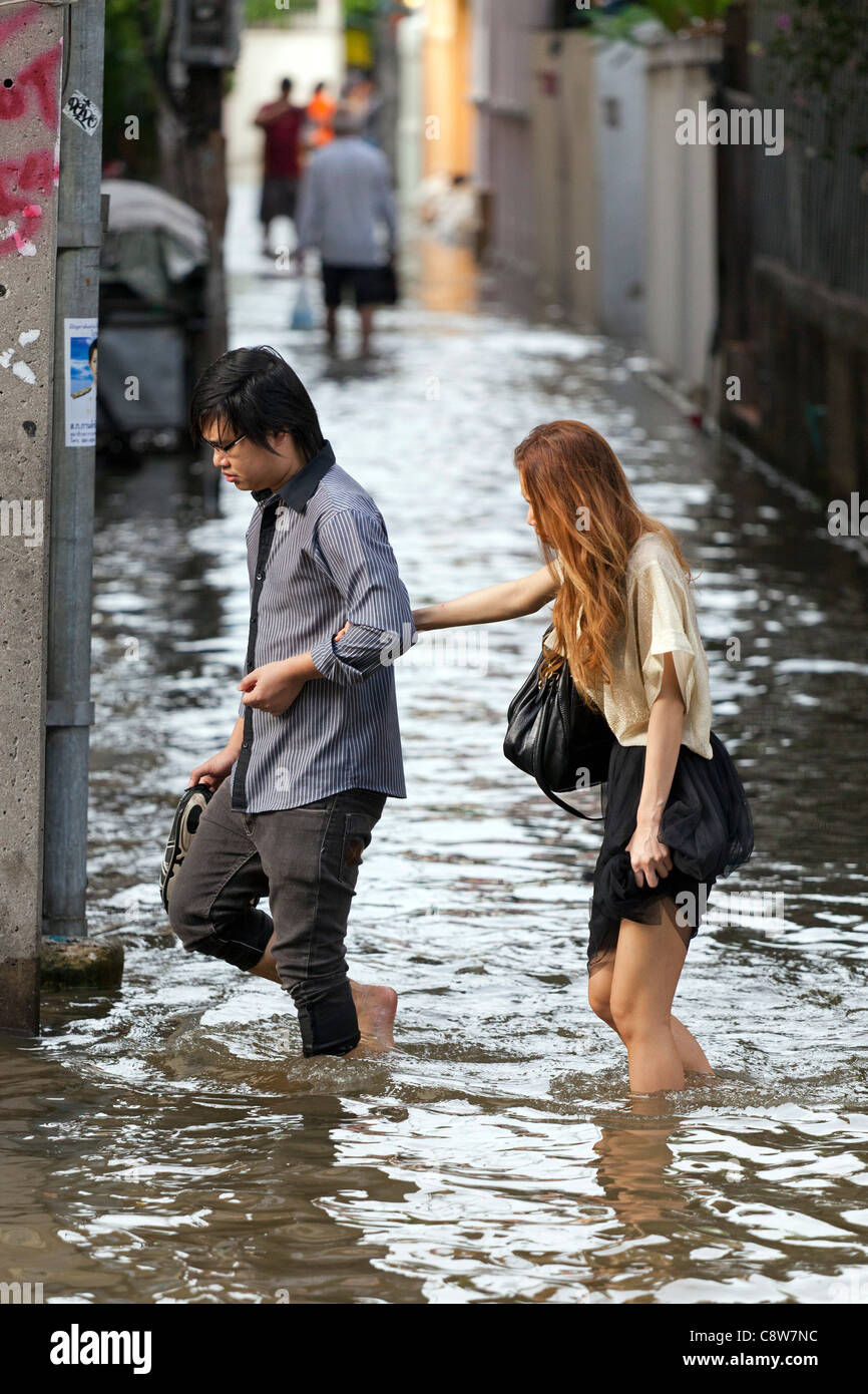 Couple walking through flood water in Bangkok city centre, Thailand ...