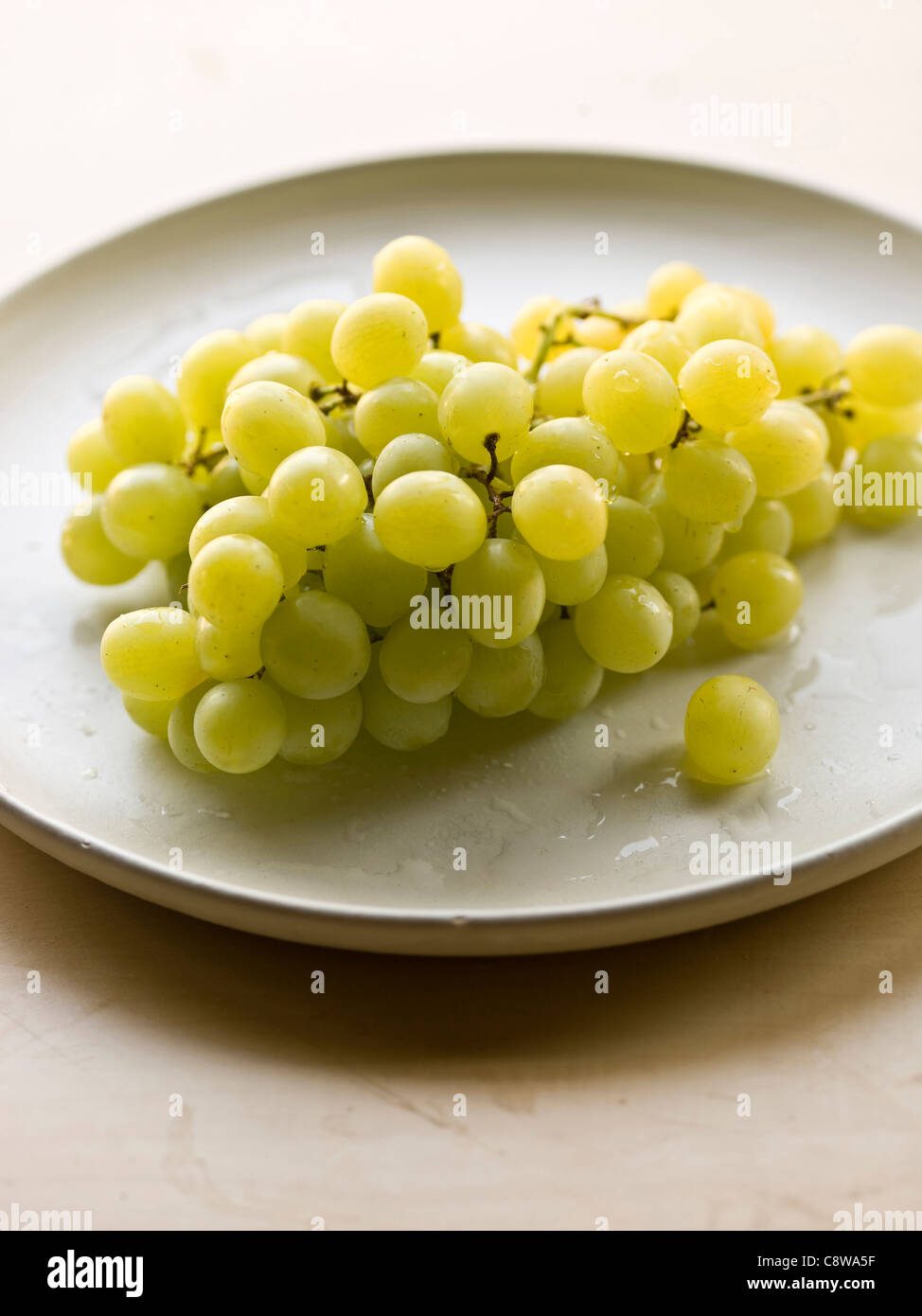 Bunch of green grapes on plate Stock Photo - Alamy
