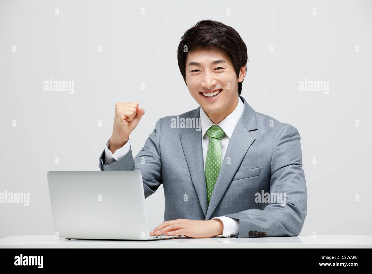 Portrait Of Businessman Clenching His Fist And Laptop On Desk Stock ...