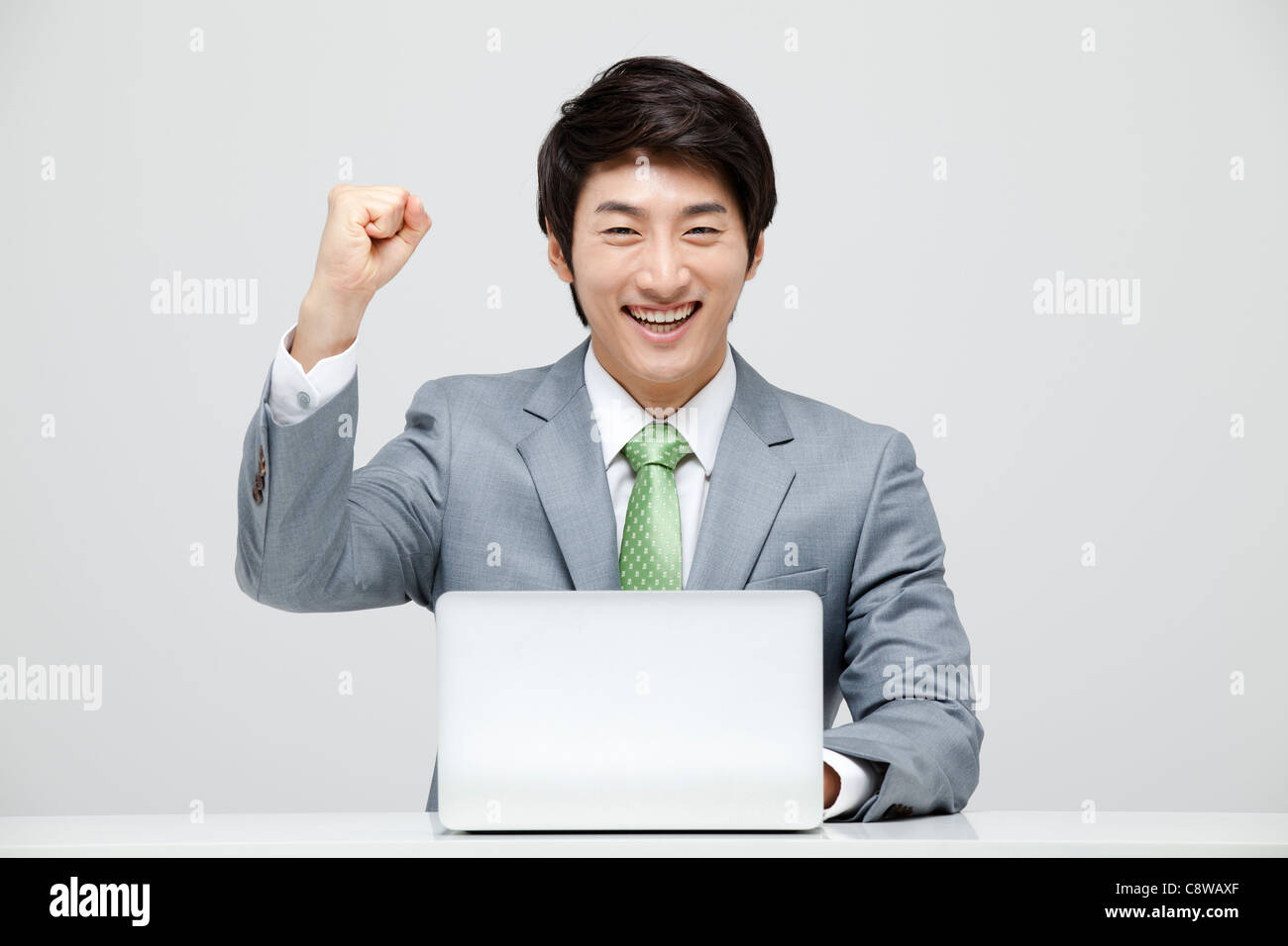 Portrait Of Businessman Clenching His Fist And Laptop On Desk Stock ...