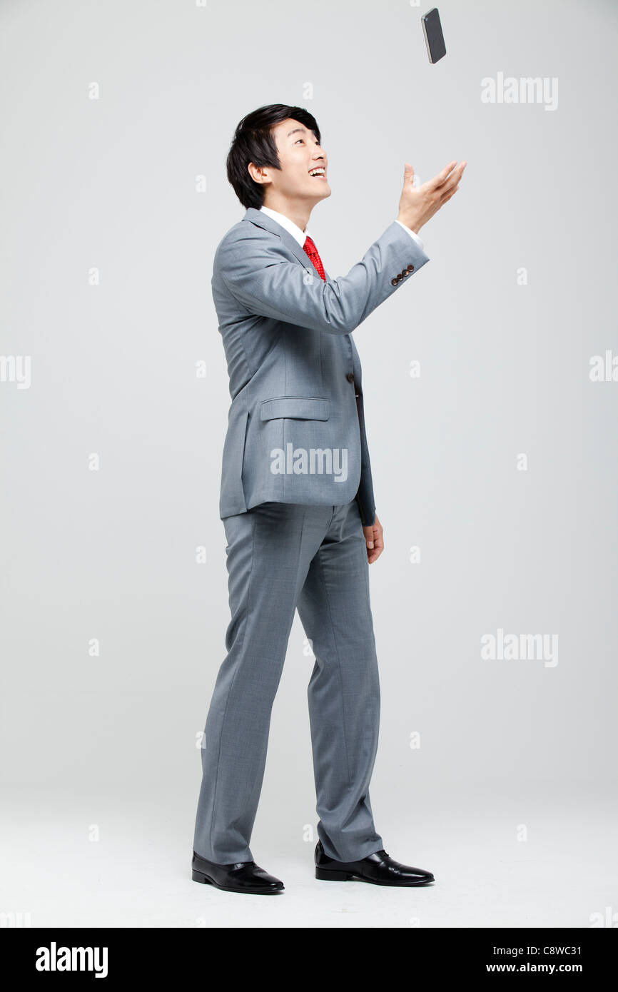 Asian Businessman Throwing Cell Phone In Air Stock Photo - Alamy