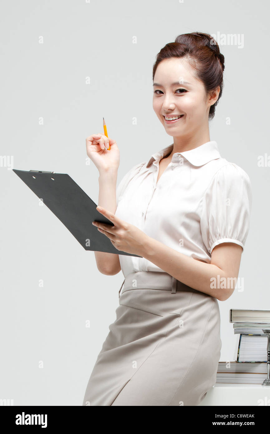 Asian Businesswoman Leaning On Desk Holding Writing Pad In Hand Stock ...