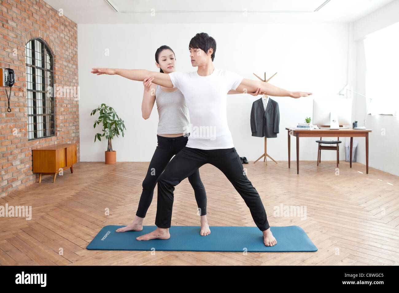 Female Instructor Helping Woman With Pose Stock Photo - Alamy