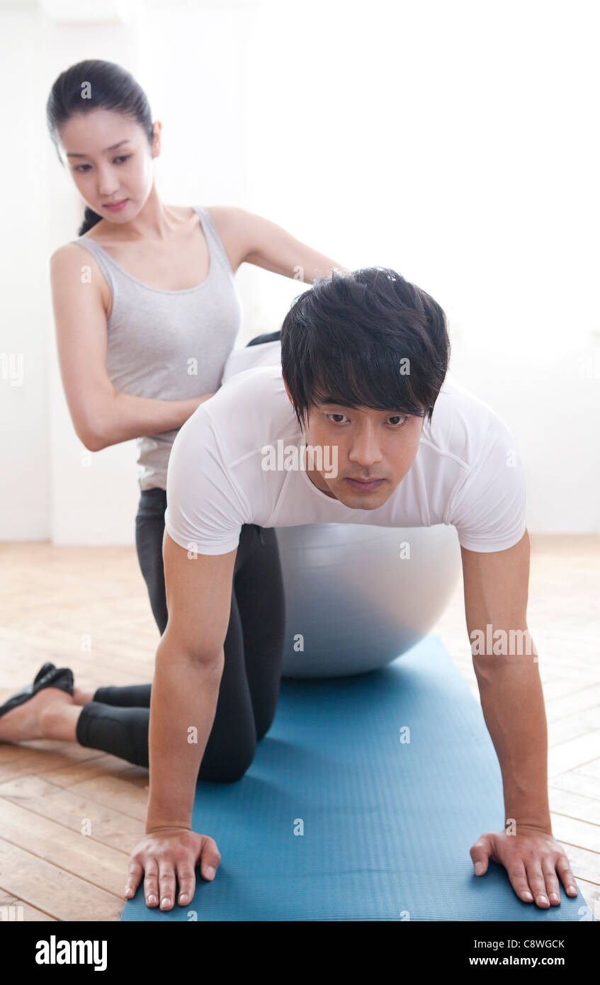 Female Instructor Helping Woman With Pose Stock Photo - Alamy