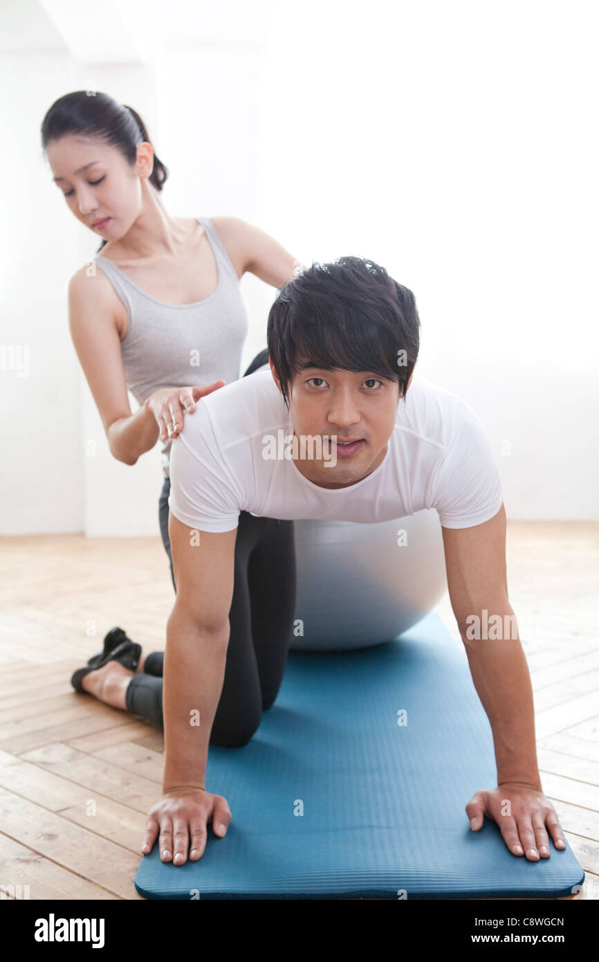 Female Instructor Helping Woman With Pose Stock Photo - Alamy