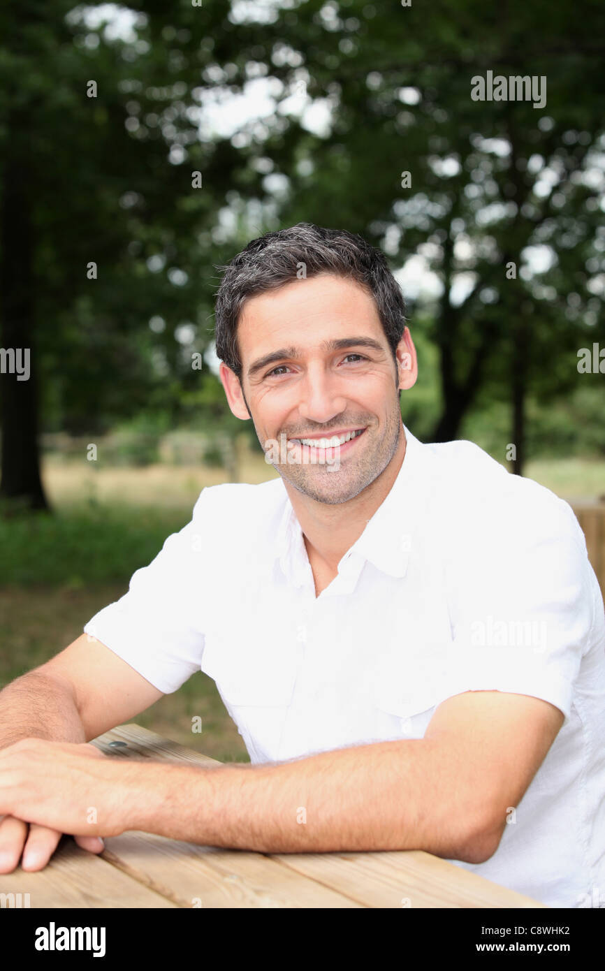 Man sitting at a table in a park Stock Photo - Alamy
