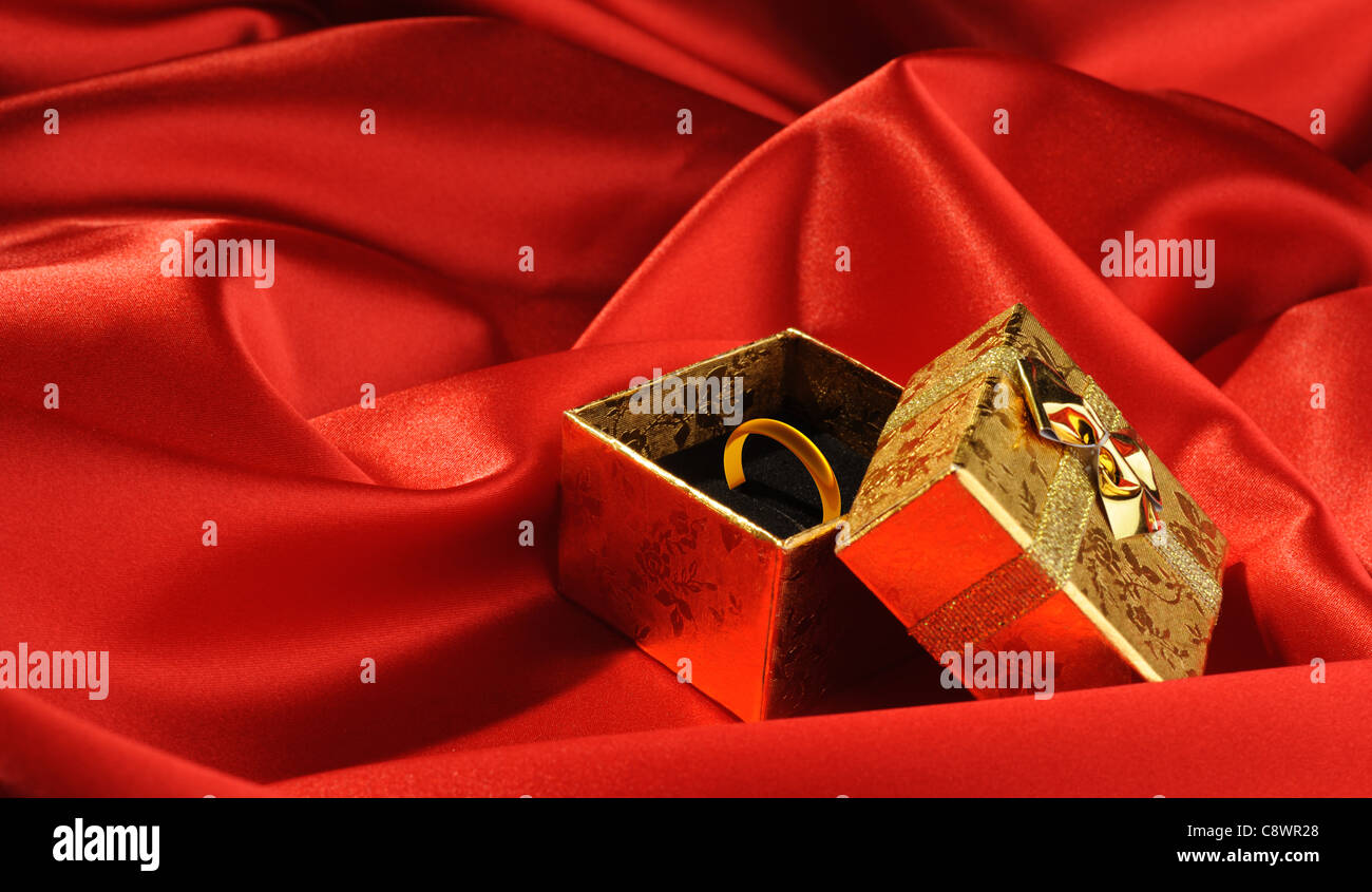 Gold boxes with a wedding ring on red silk Stock Photo - Alamy
