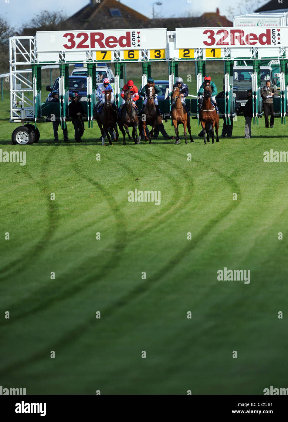 Racehorses and Jockeys leave the starting stalls at the start of a race ...