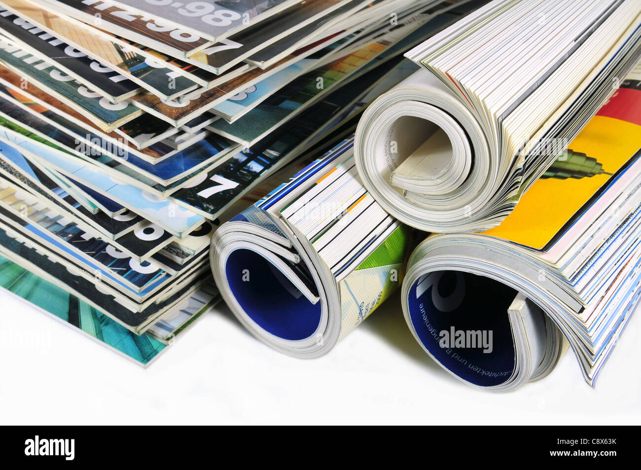 Pile of various multicolored stack and rolled up magazines on white ...
