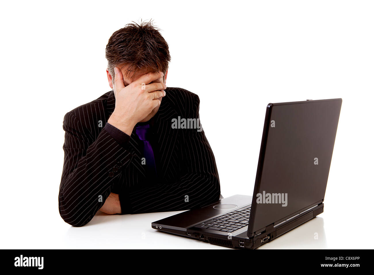 Businessman sitting behind desk is in despair, covering his eyes, over ...