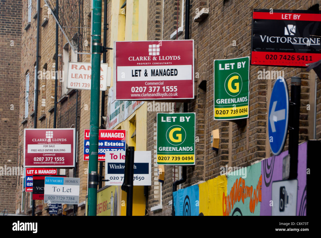 Cluster of 'To Let', 'Let By' and 'For Sale' signs on buildings in ...