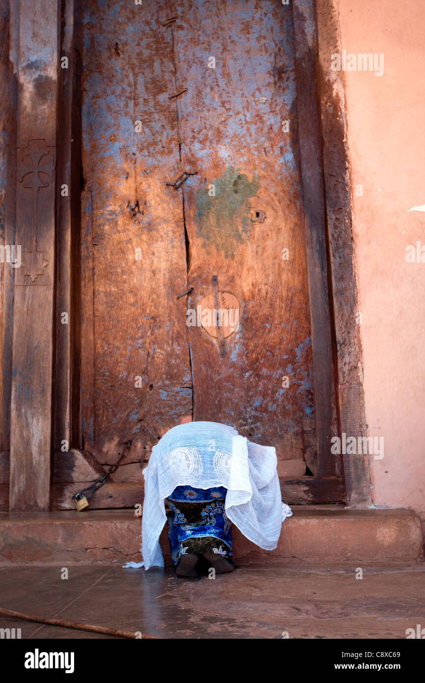 A Local devotee at the entrance to the rock-hewn church of Abraha ...