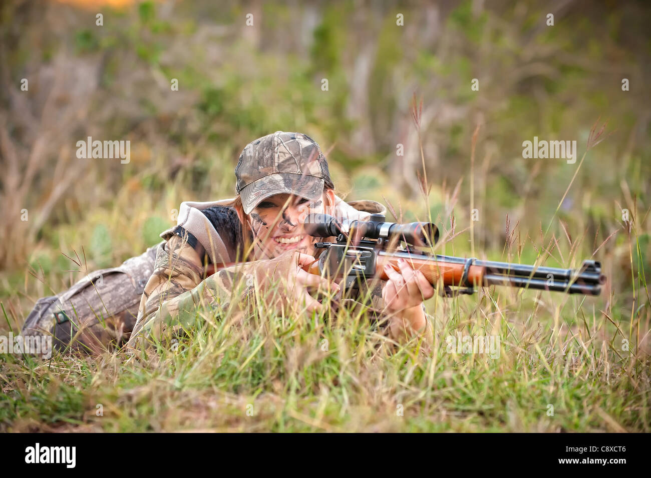 Smiling female hunter lying on the ground while being happy Stock Photo ...