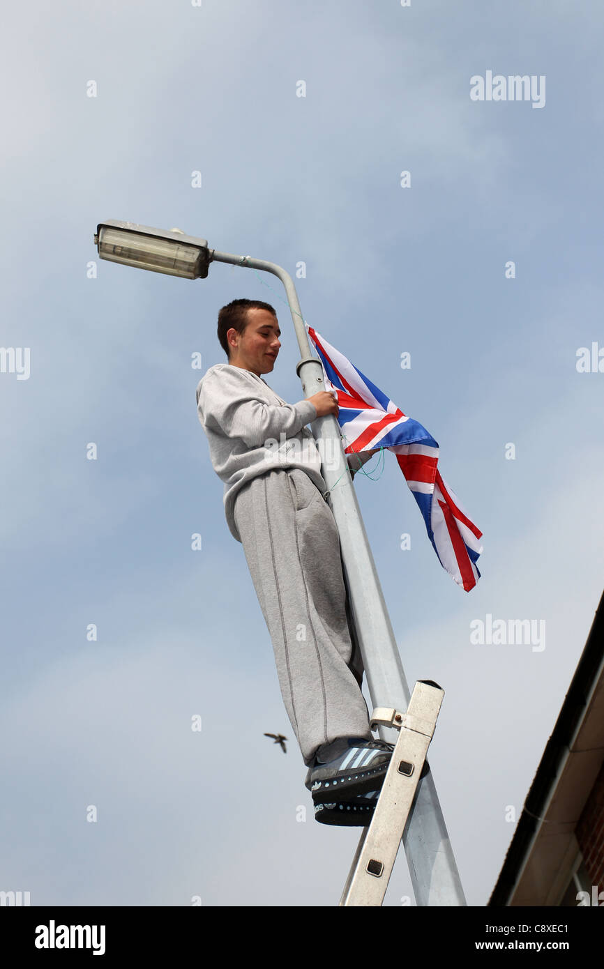 Man putting up a Union Jack flag to celebrate the Royal Wedding at a ...