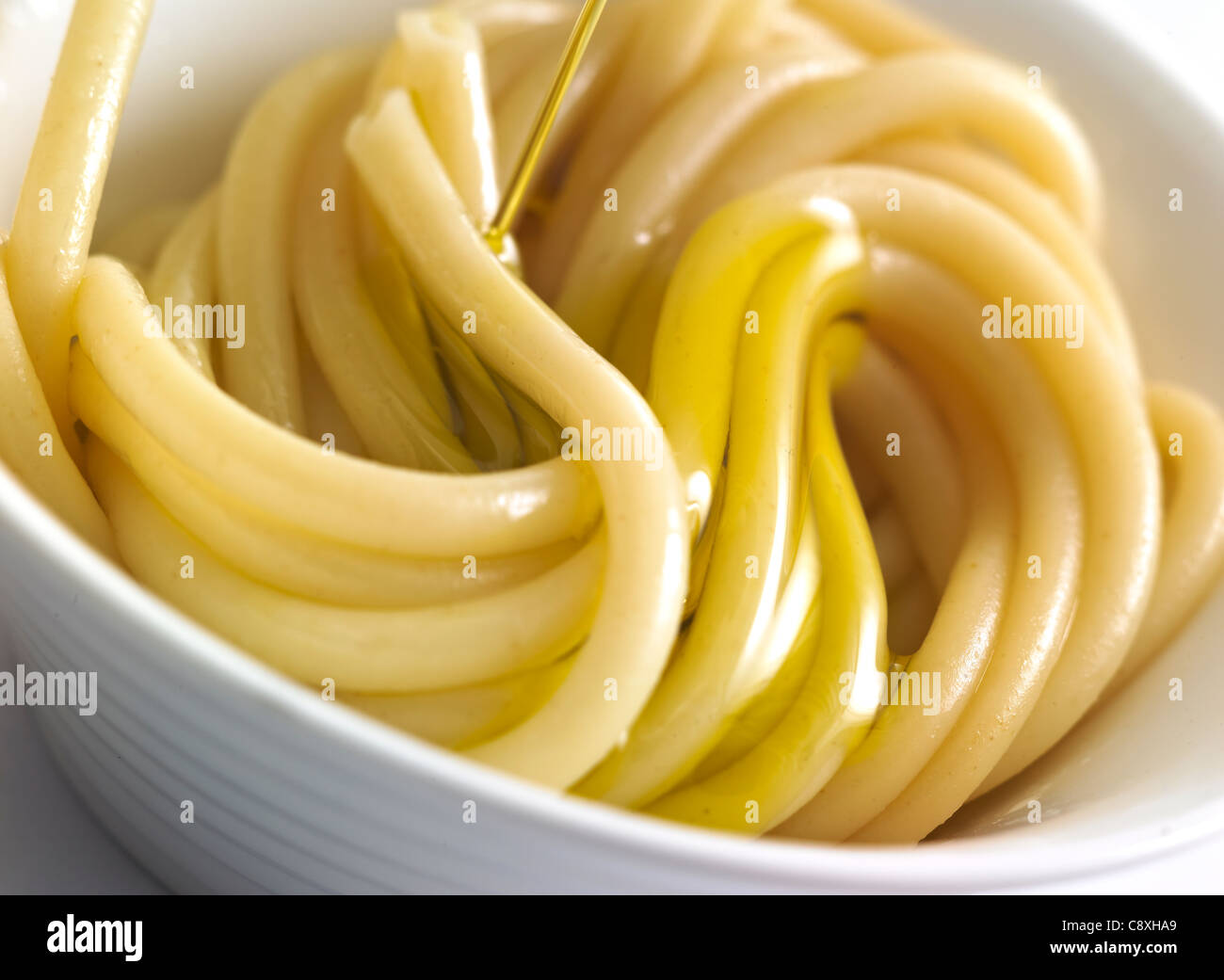 swirl of bucotinni spaghetti in bowl with olive oil being poured Stock ...