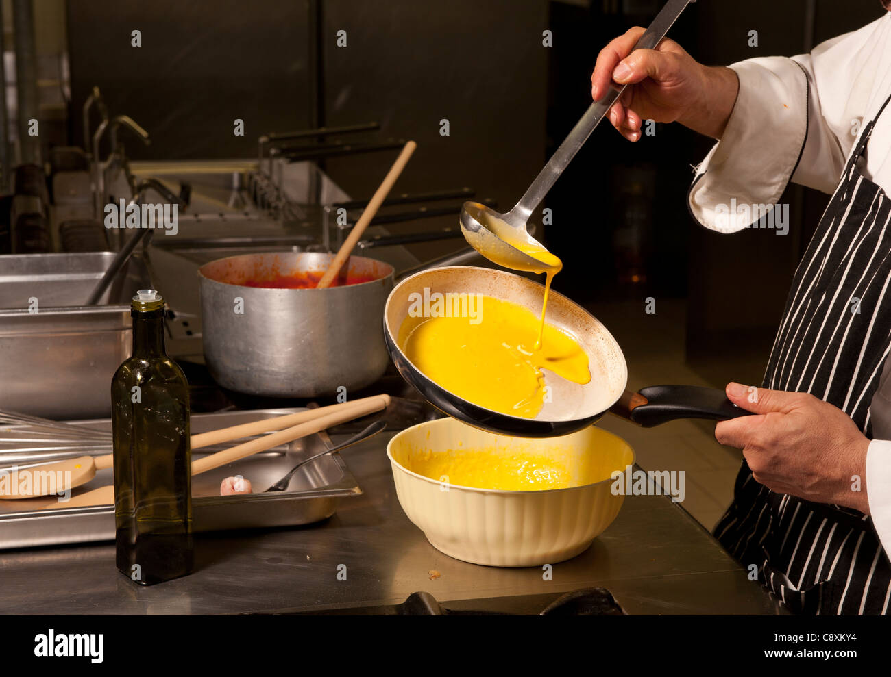 professional chef using ladle to pour mixture into pan to make crepes ...