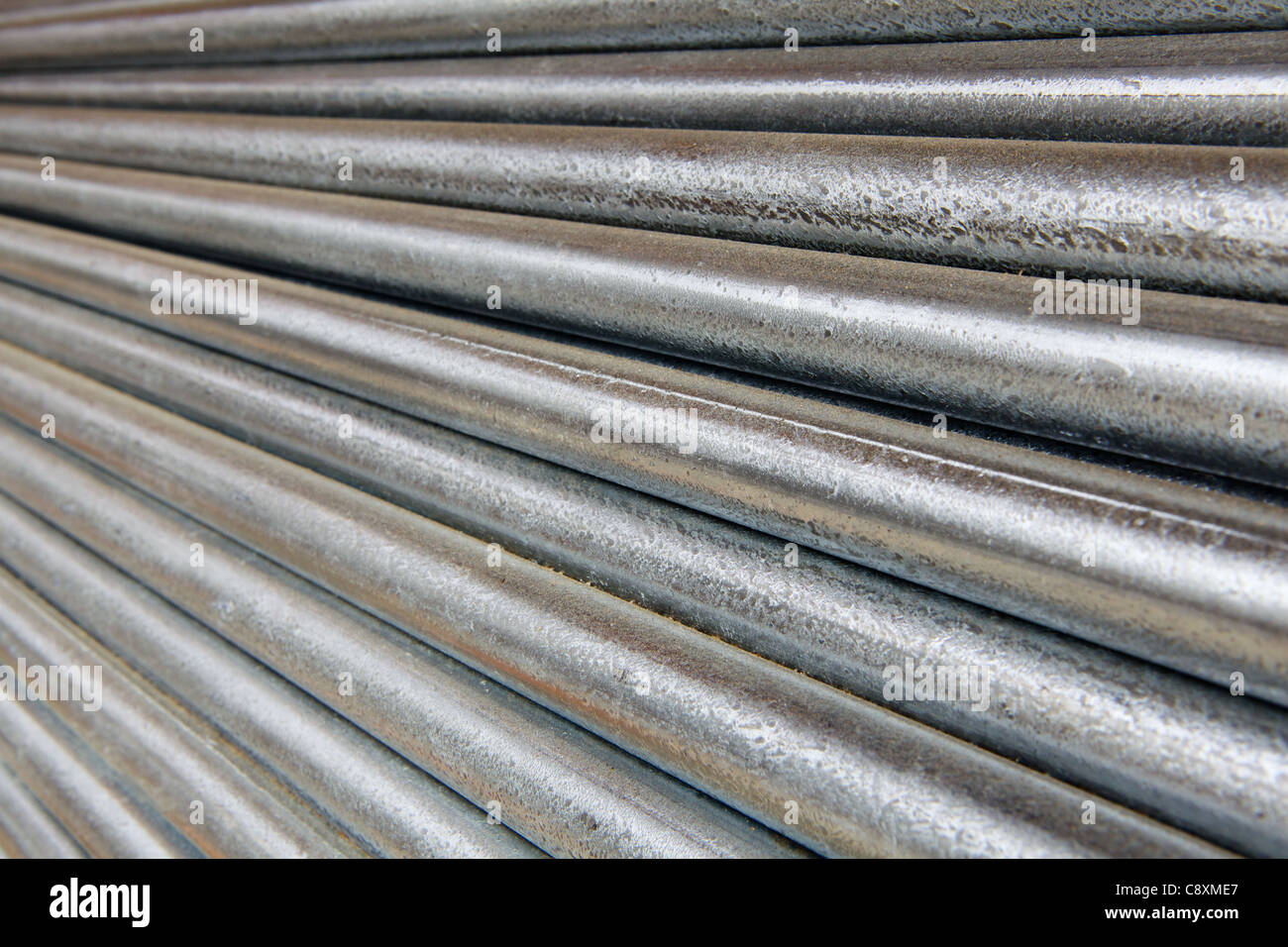 Pile of shiny galvanized steel pipe diminishing from right to left ...