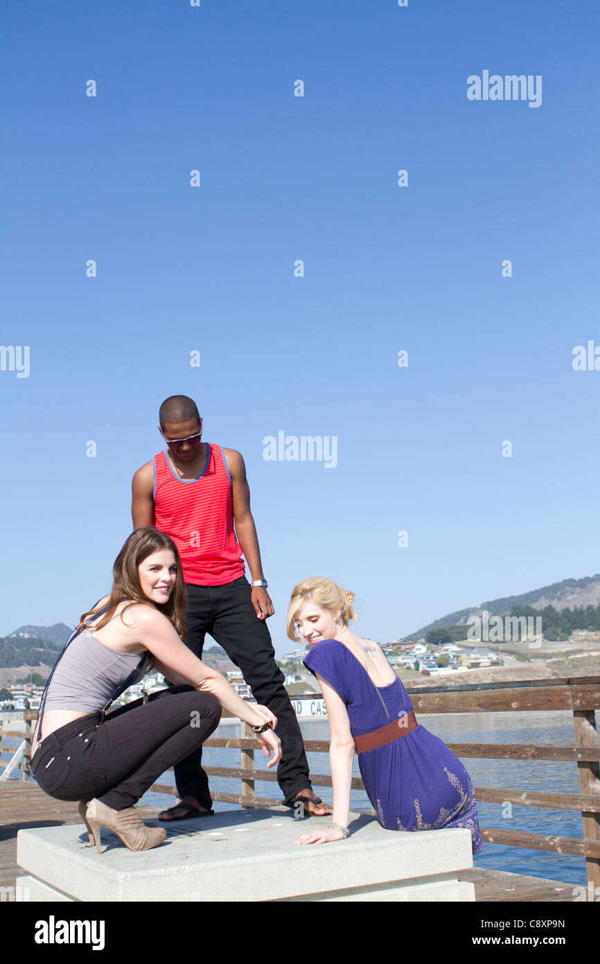 Three people hanging out on a pier Stock Photo - Alamy