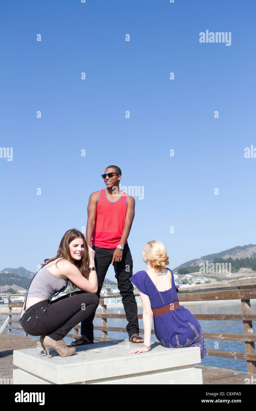Three people hanging out on a pier Stock Photo - Alamy