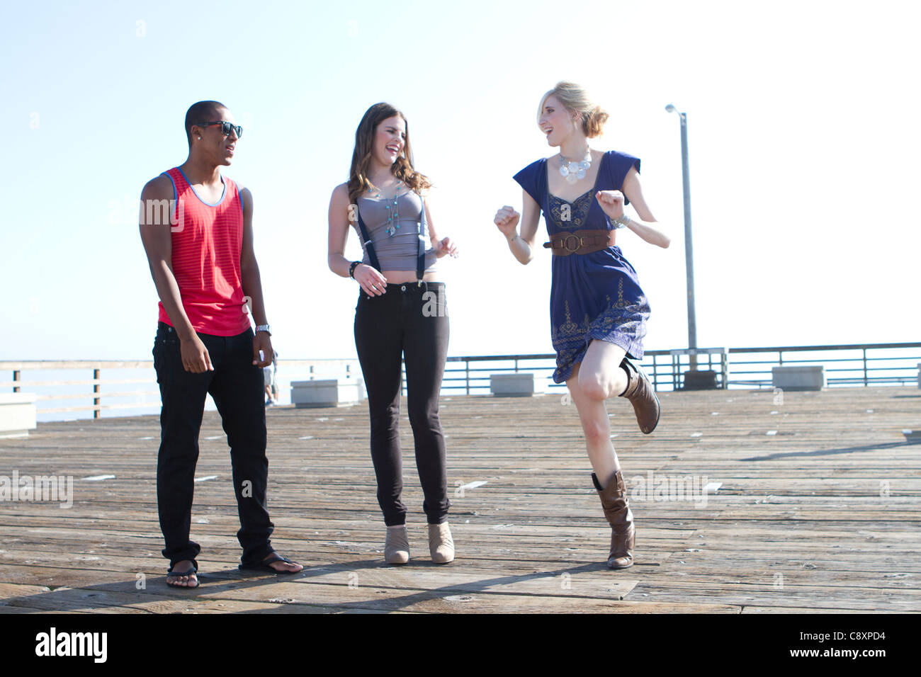 Three young people being silly on a pier Stock Photo - Alamy