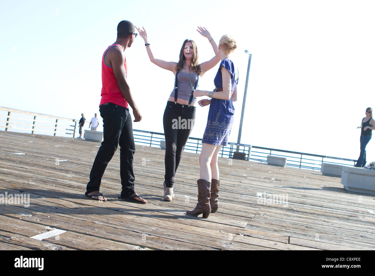 Three young people being silly on a pier Stock Photo - Alamy