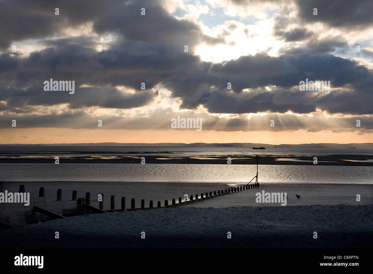 Winter evening sun rays breaking through clouds onto the beach Stock ...