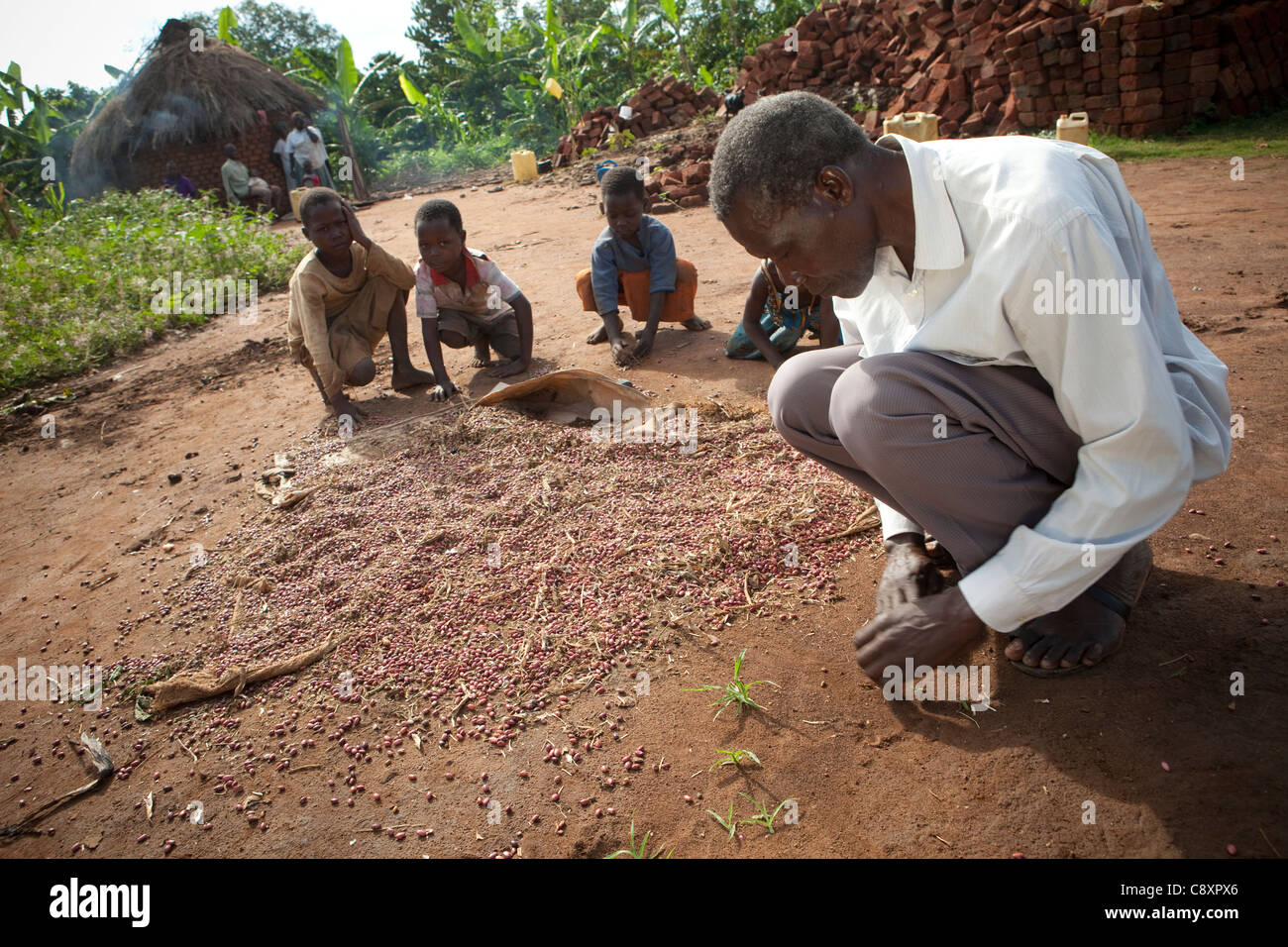 A family gather their small bean harvest outside their home in Nsinze ...