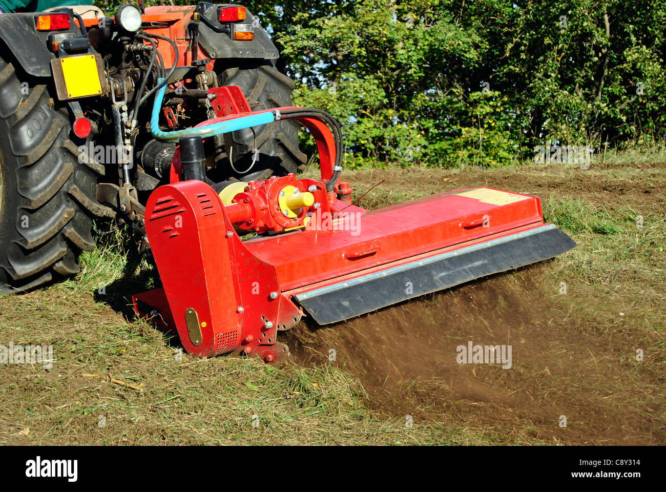 Small farm tractor bush hogging on a grass field in Trentino Alto Adige ...