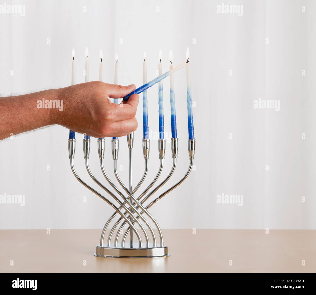 Man's hand lighting menorah Stock Photo - Alamy