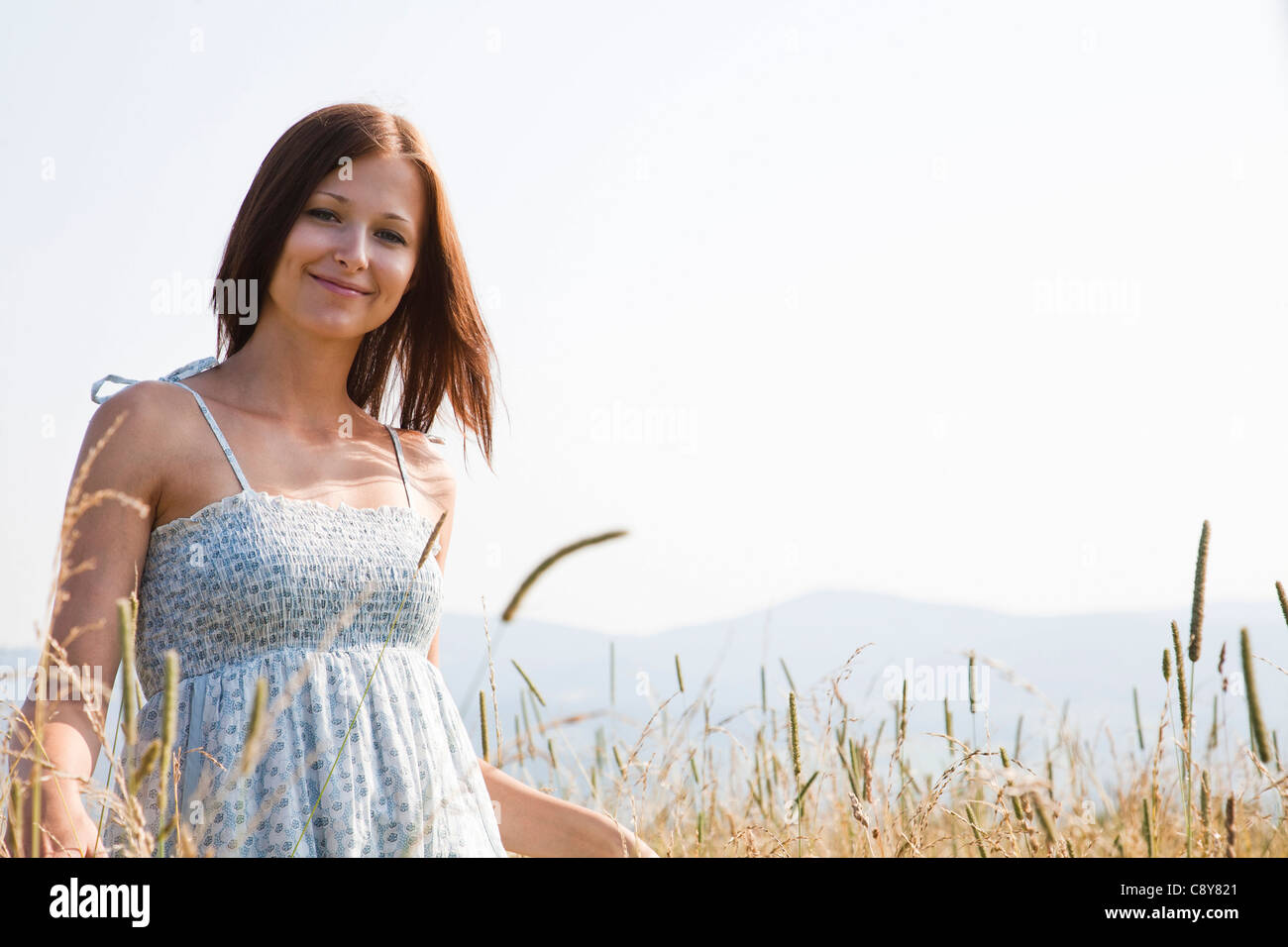 portrait of young woman standing in field Stock Photo - Alamy