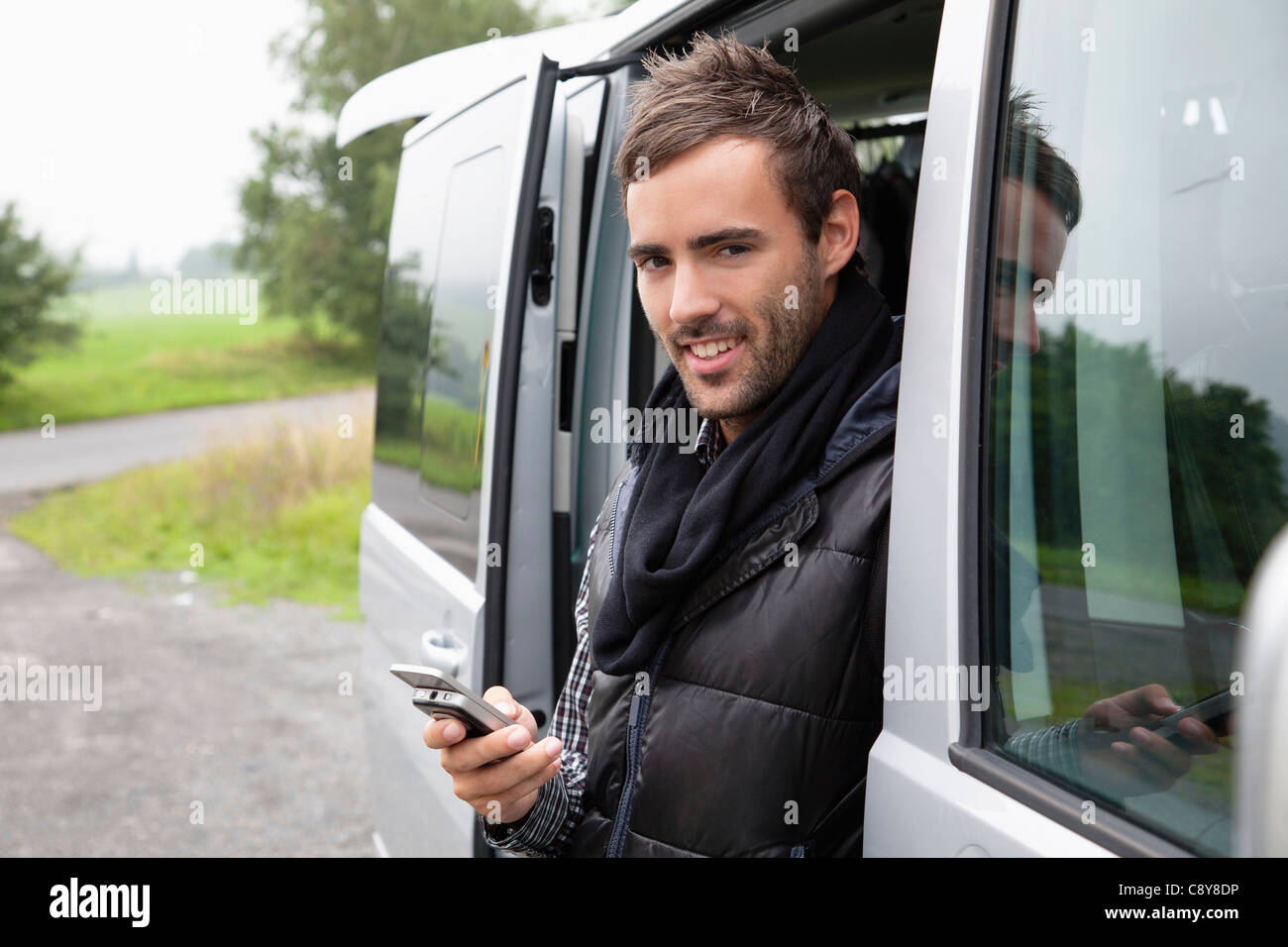 portrait of young man looking out of car window writing text message on ...