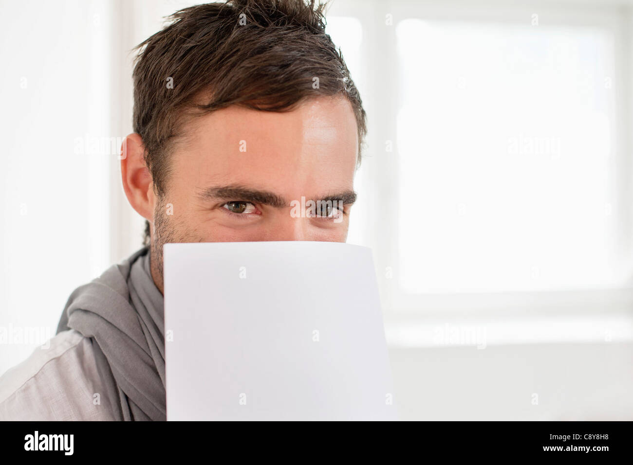 headshot of young man hiding behind document Stock Photo - Alamy