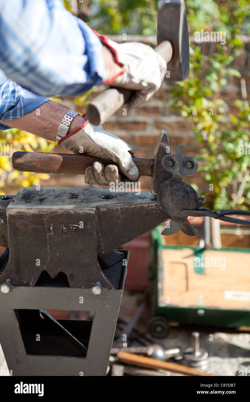 Blacksmith hammering a piece of iron to give it a shape Stock Photo - Alamy