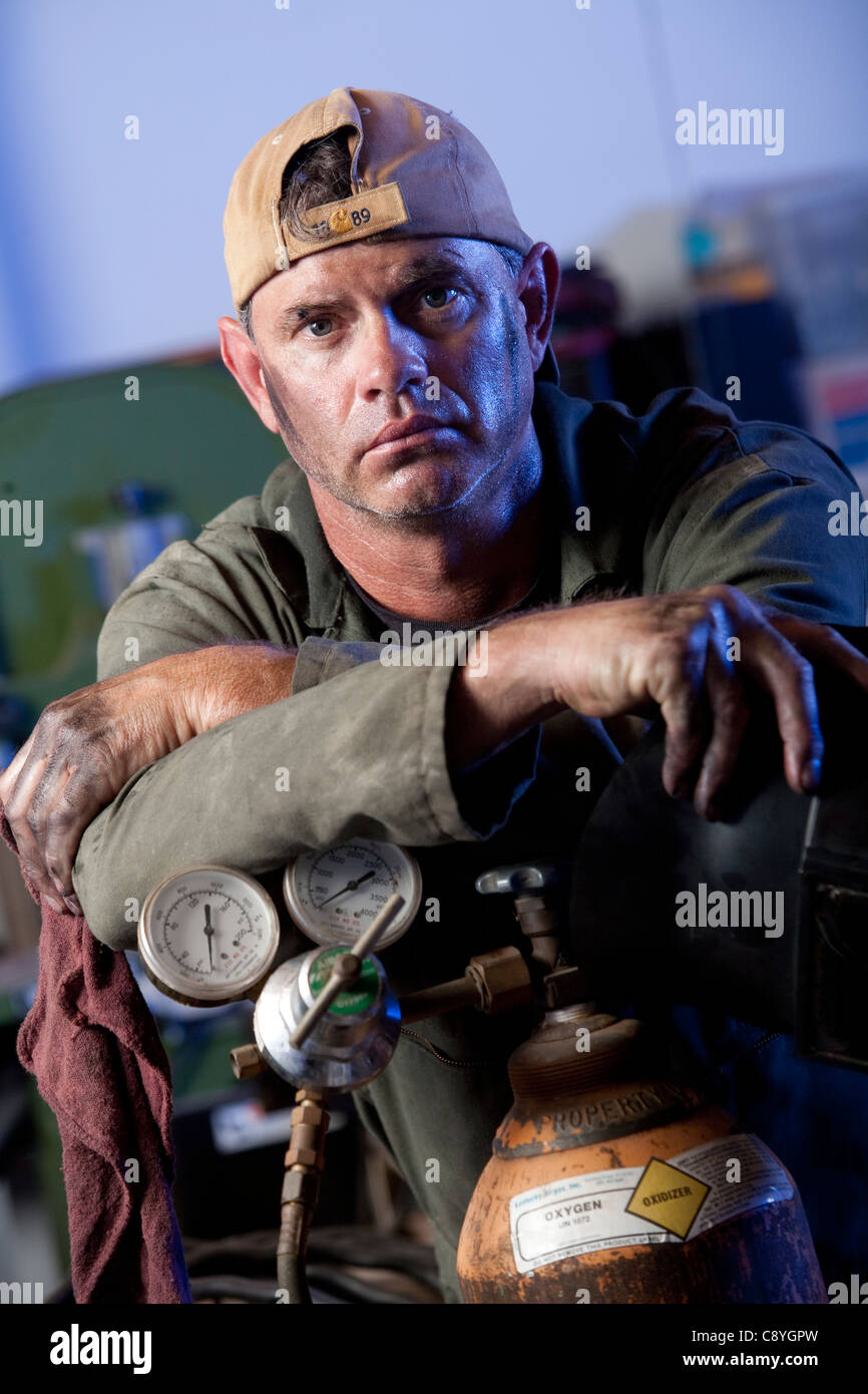 A grease covered blue collar working man takes a break, looking ...