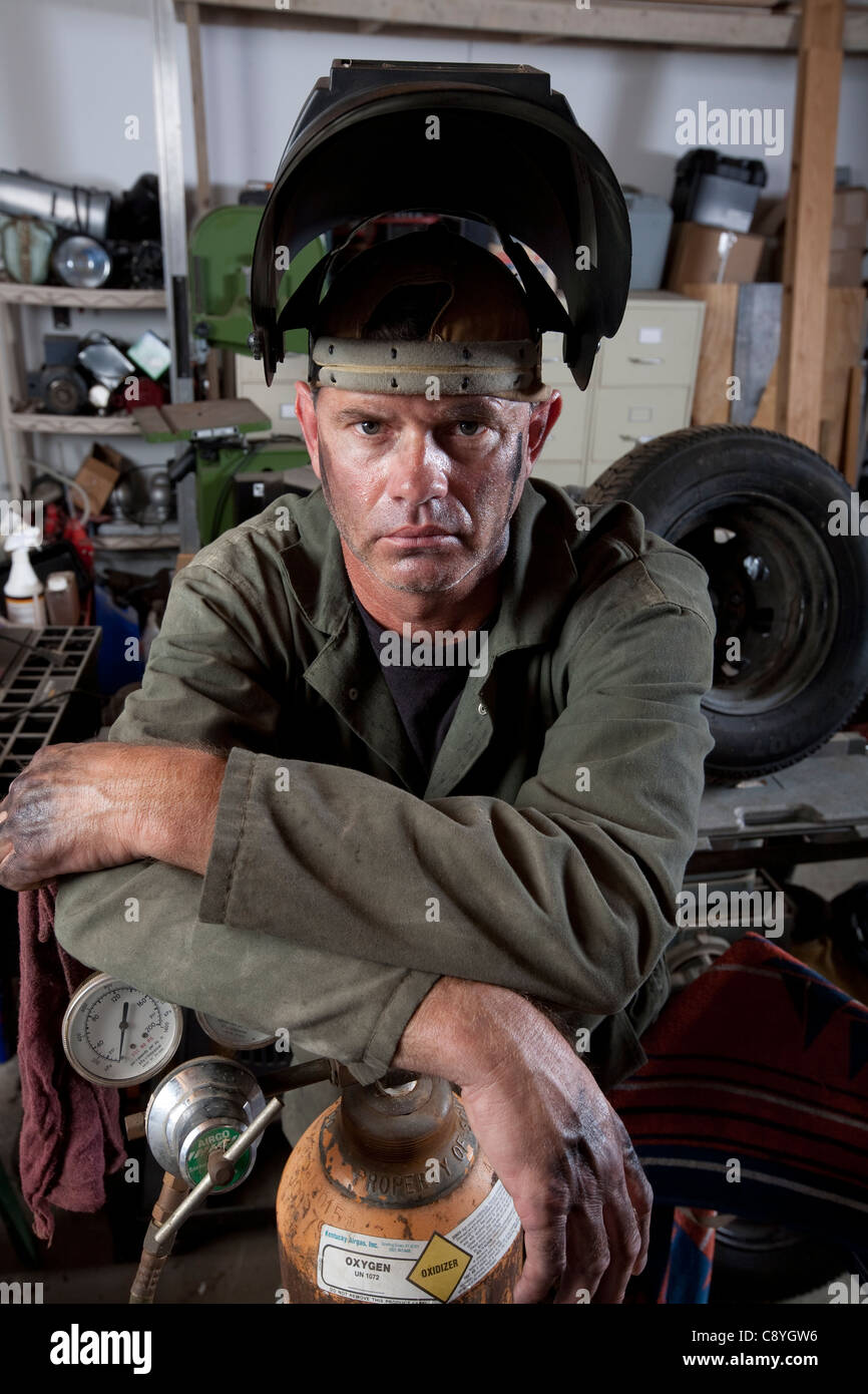 A grease covered blue collar working man takes a break, looking ...