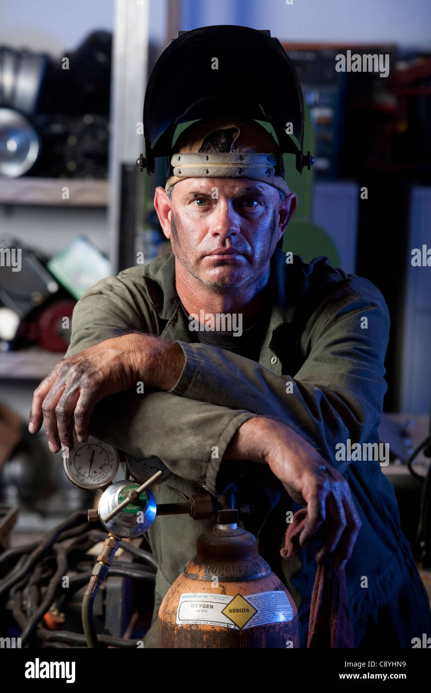 A grease covered blue collar working man takes a break, looking ...