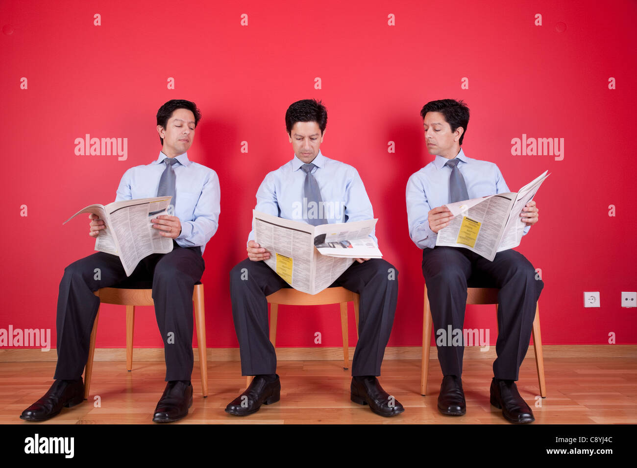 Three businessman peeking and reading the newspaper siting on a chair ...