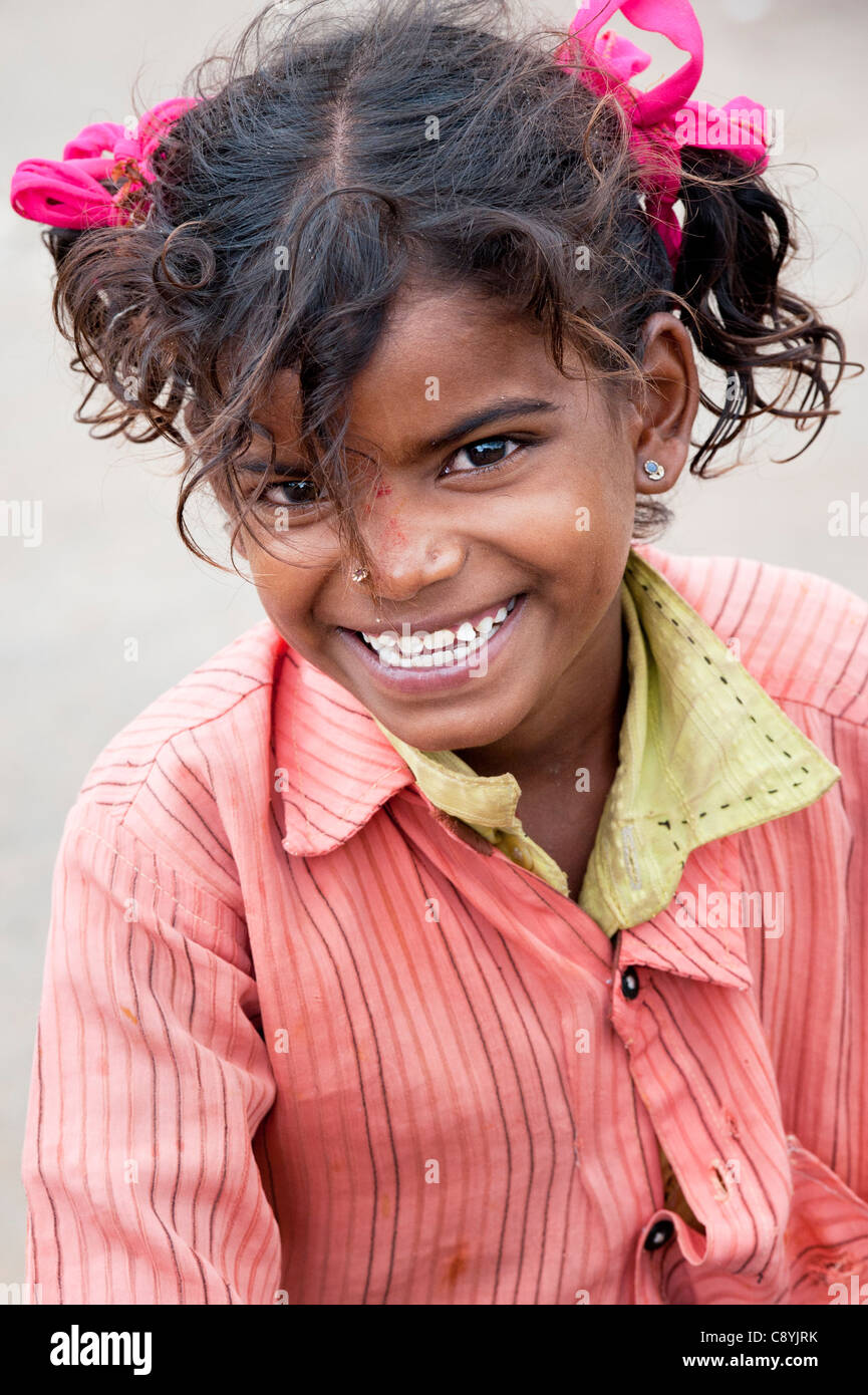 Poor Indian gypsy girl smiling with pink ribbons in her hair. Andhra ...