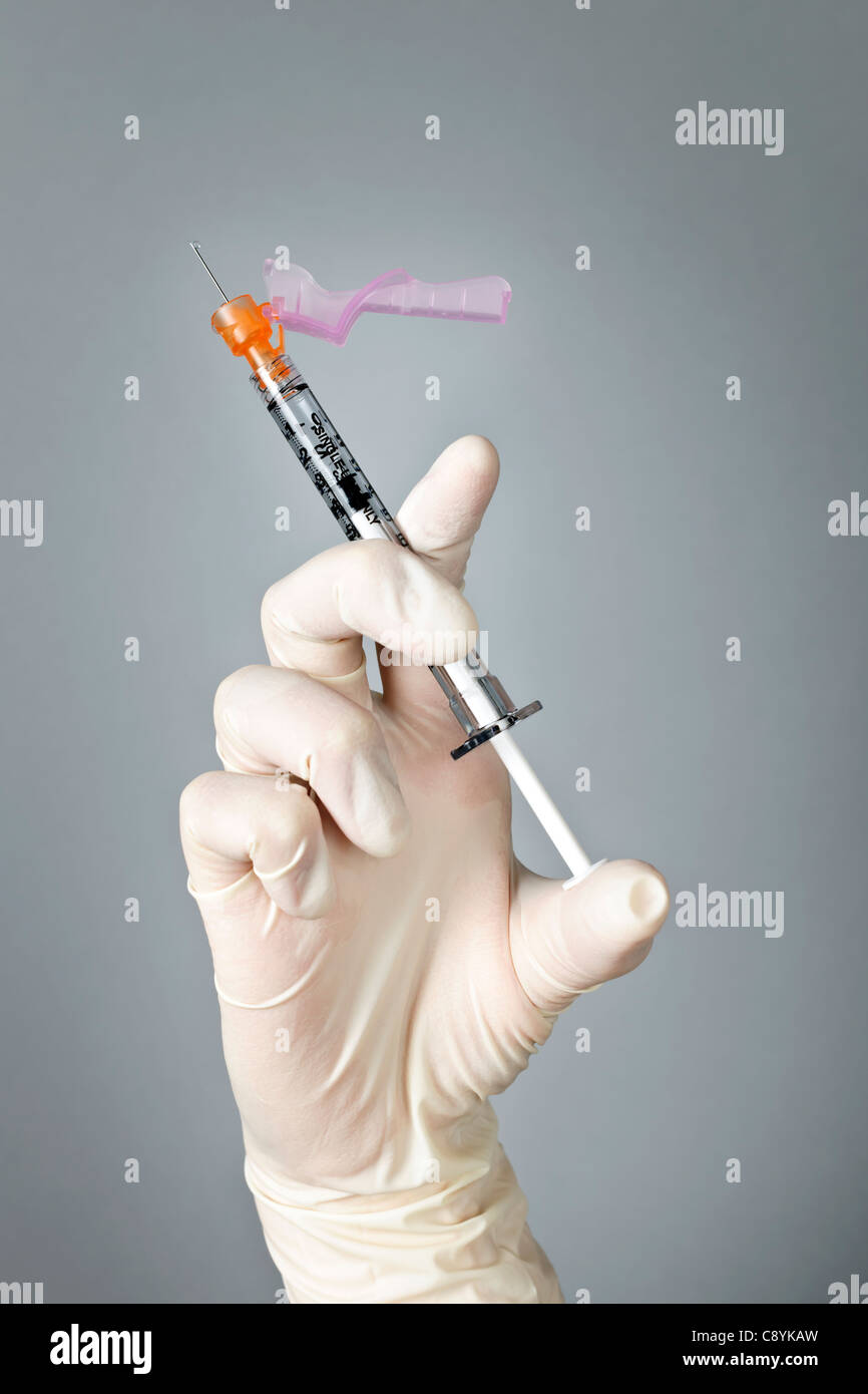 Medical safety syringe held by hand in surgical latex glove Stock Photo ...